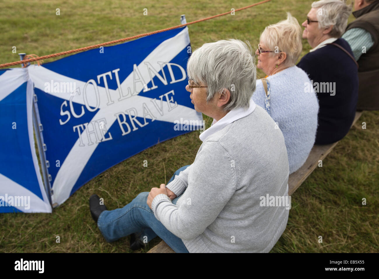 Ladies sitting next to a Scottish flag watching a pipe band at the ...