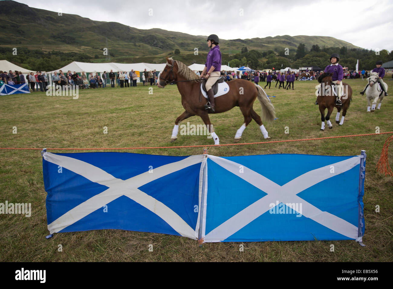 Horse riders parading past two Scottish flags at the Dalmally ...