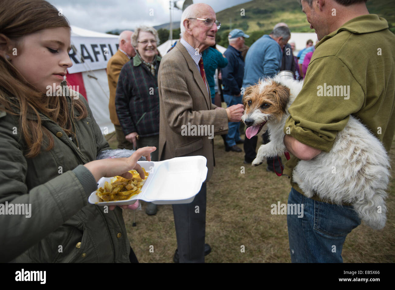 A terrier dog looking at a girl eating potato chips at the Dalmally ...