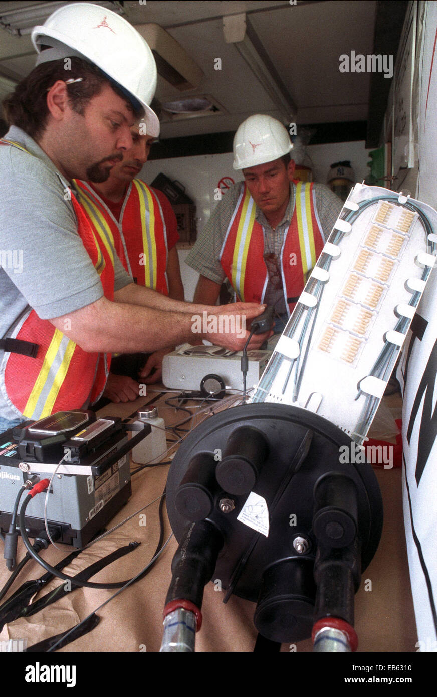 Workers splice fiber optic cables in a mobile fiber optic splicing ...