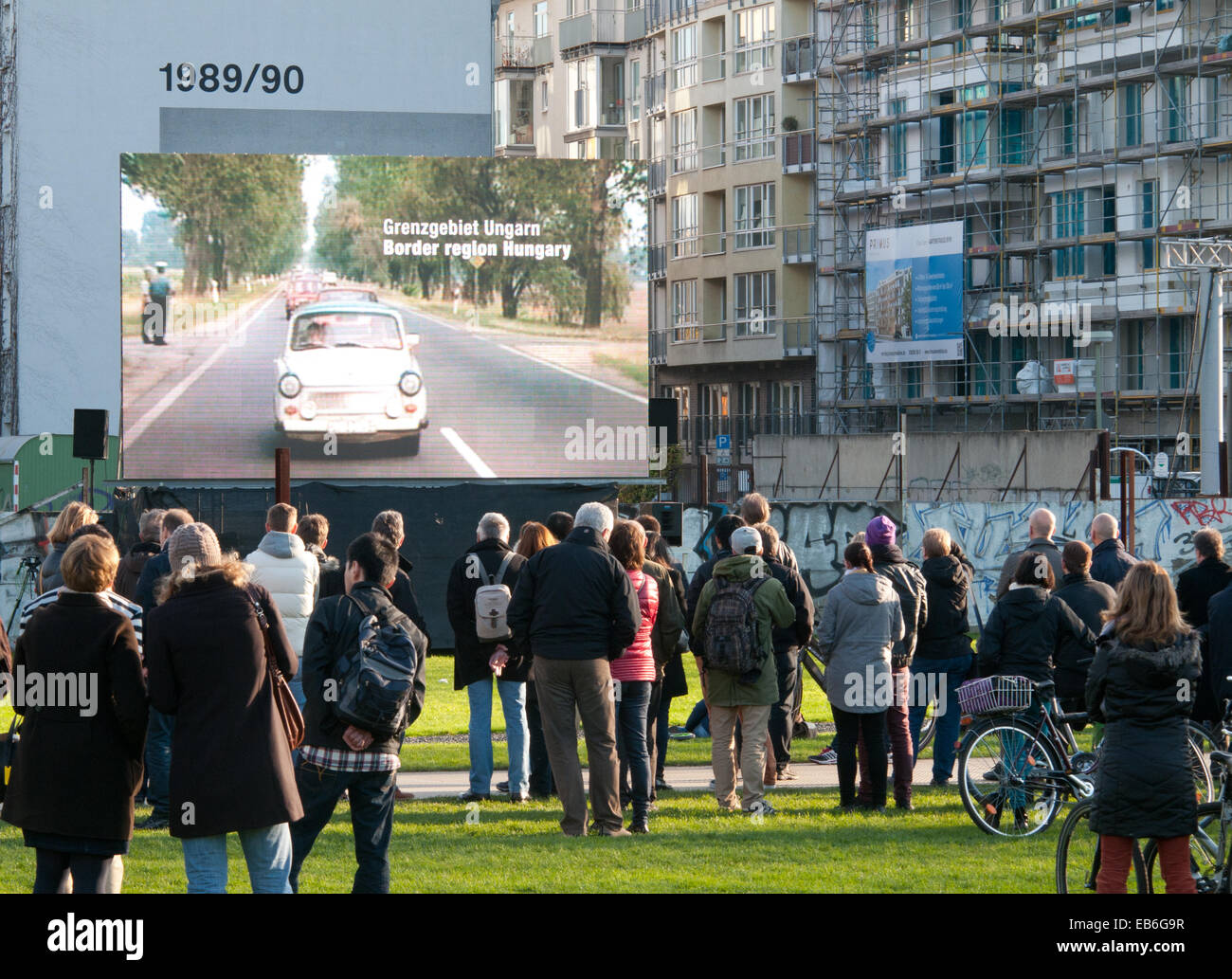 Crowd watching film about fall of Berlin Wall on public screen at ...