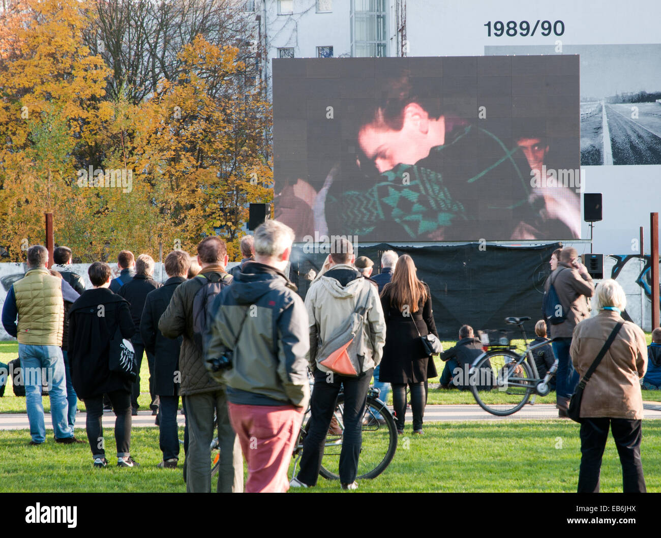 Crowd watching film about fall of Berlin Wall on public screen at ...
