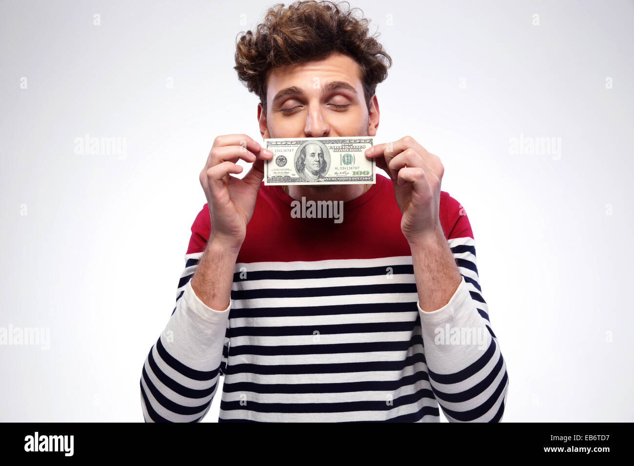 Happy man kissing dollar bill over gray background Stock Photo - Alamy