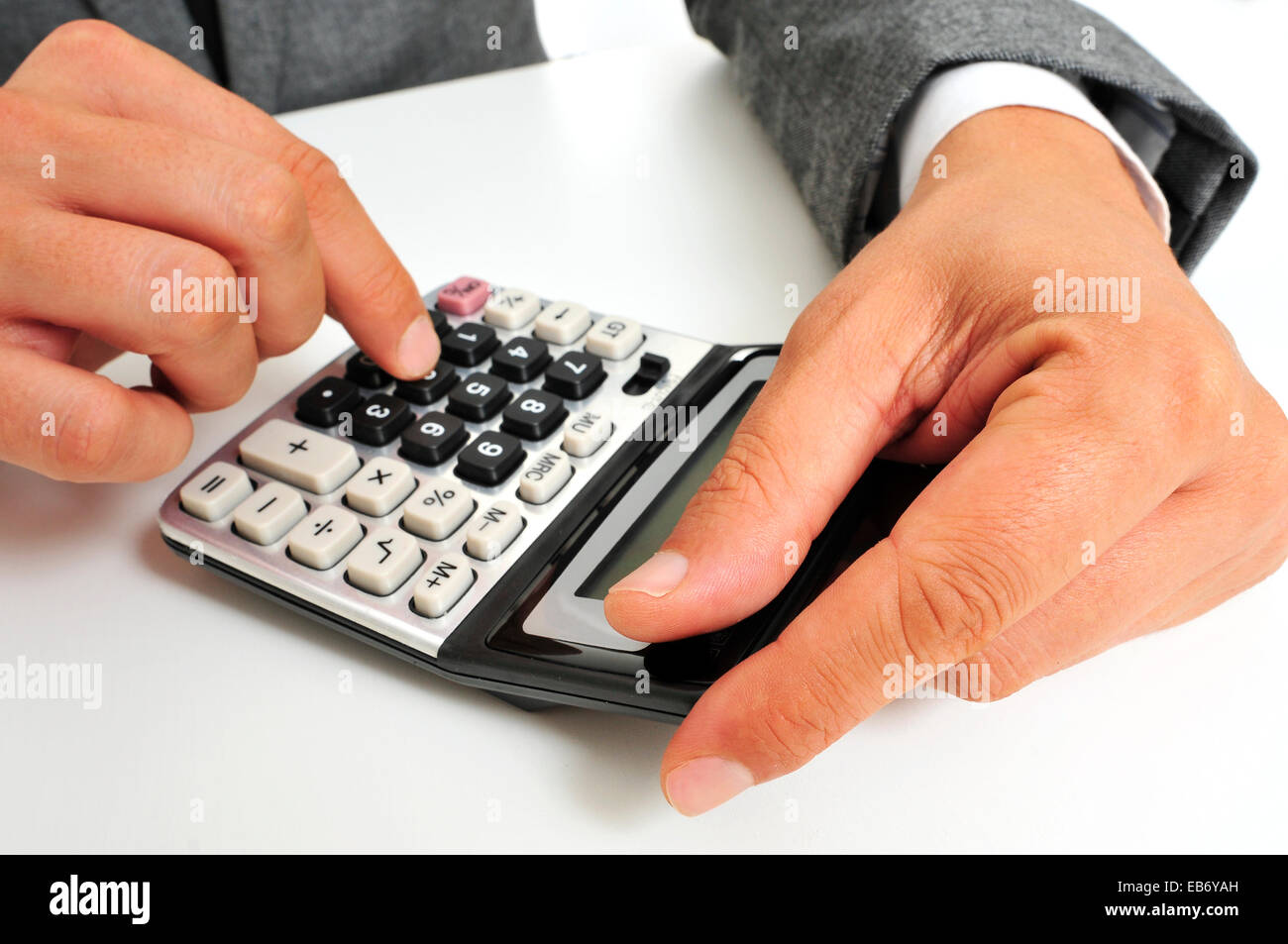 a businessman sitting in a desk using a calculator Stock Photo - Alamy