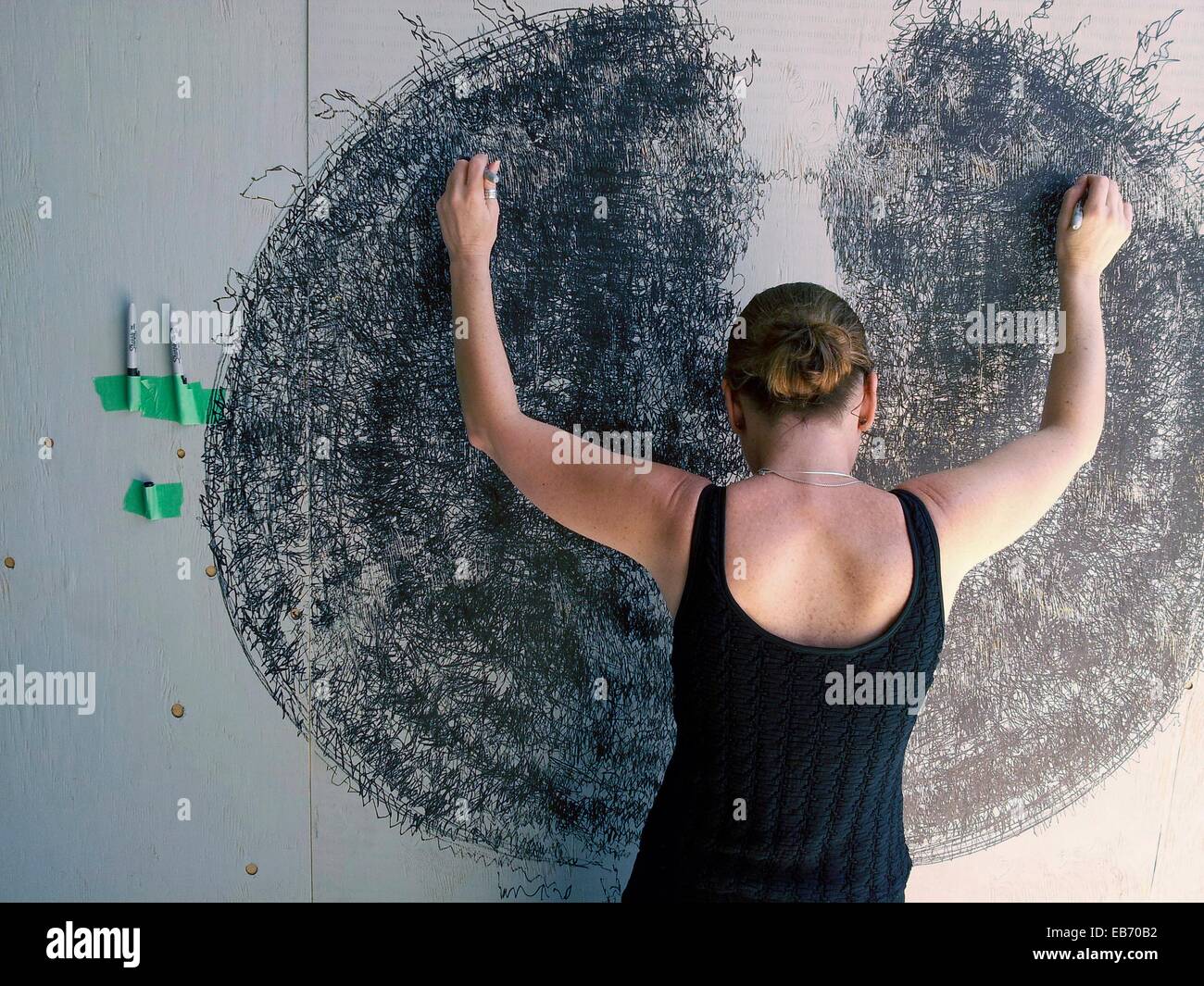 A woman artist works on public ""performance painting"" on construction ...