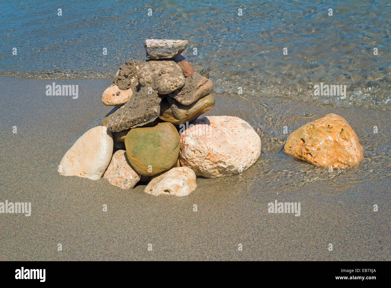 Small multi-colored sea stones on the beach, covered with transparent ...