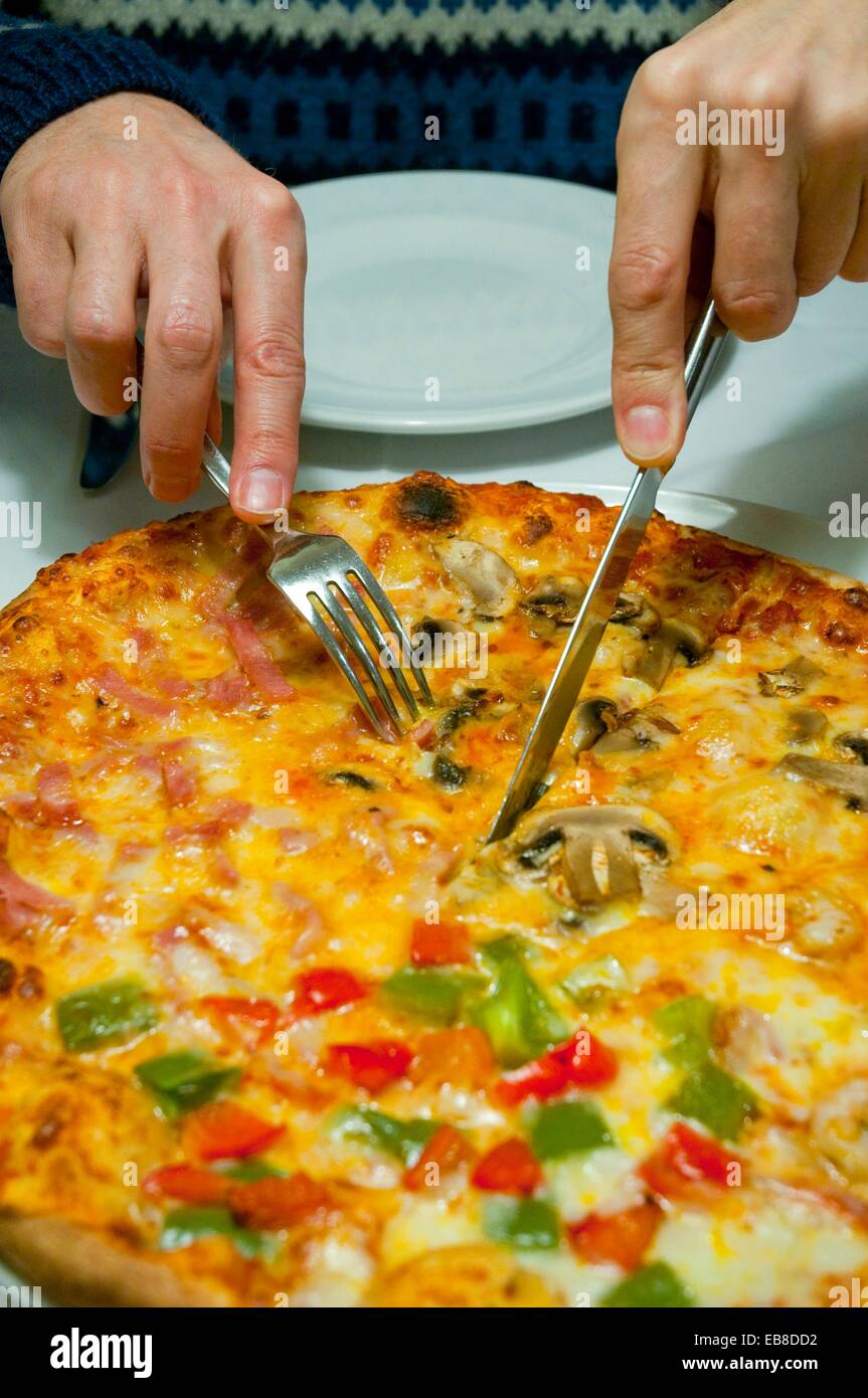 Man´s hand cutting a piece of pizza. Close view Stock Photo - Alamy