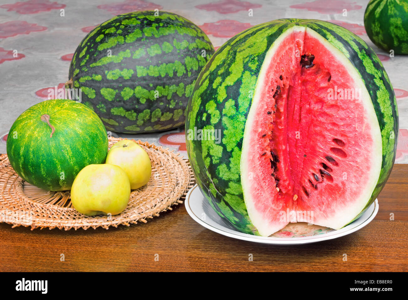 The dish is a large ripe sliced watermelon, near watermelons smaller ...