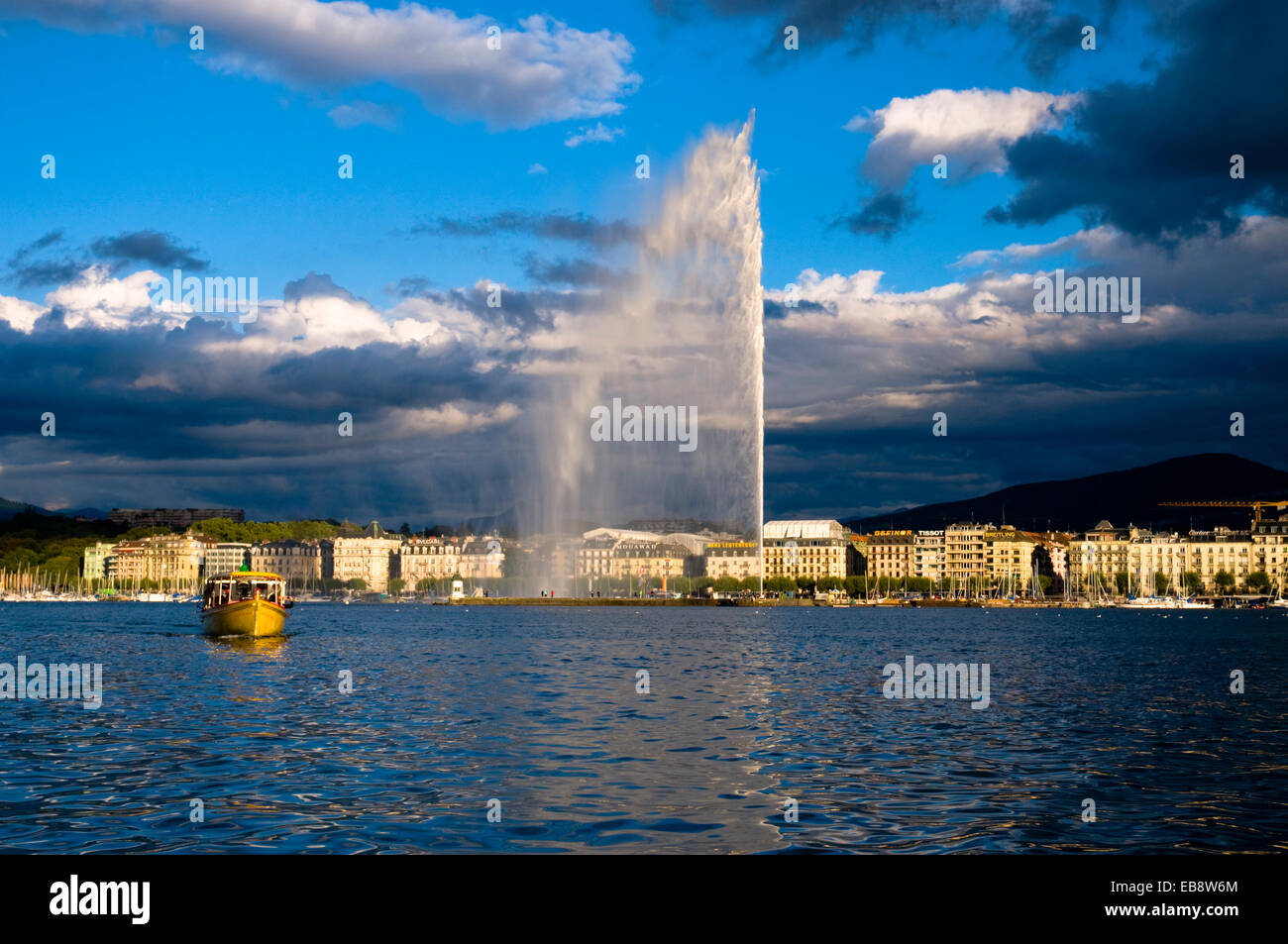 The Jet d'Eau in Geneva. A yellow mouette ferries passengers past the ...