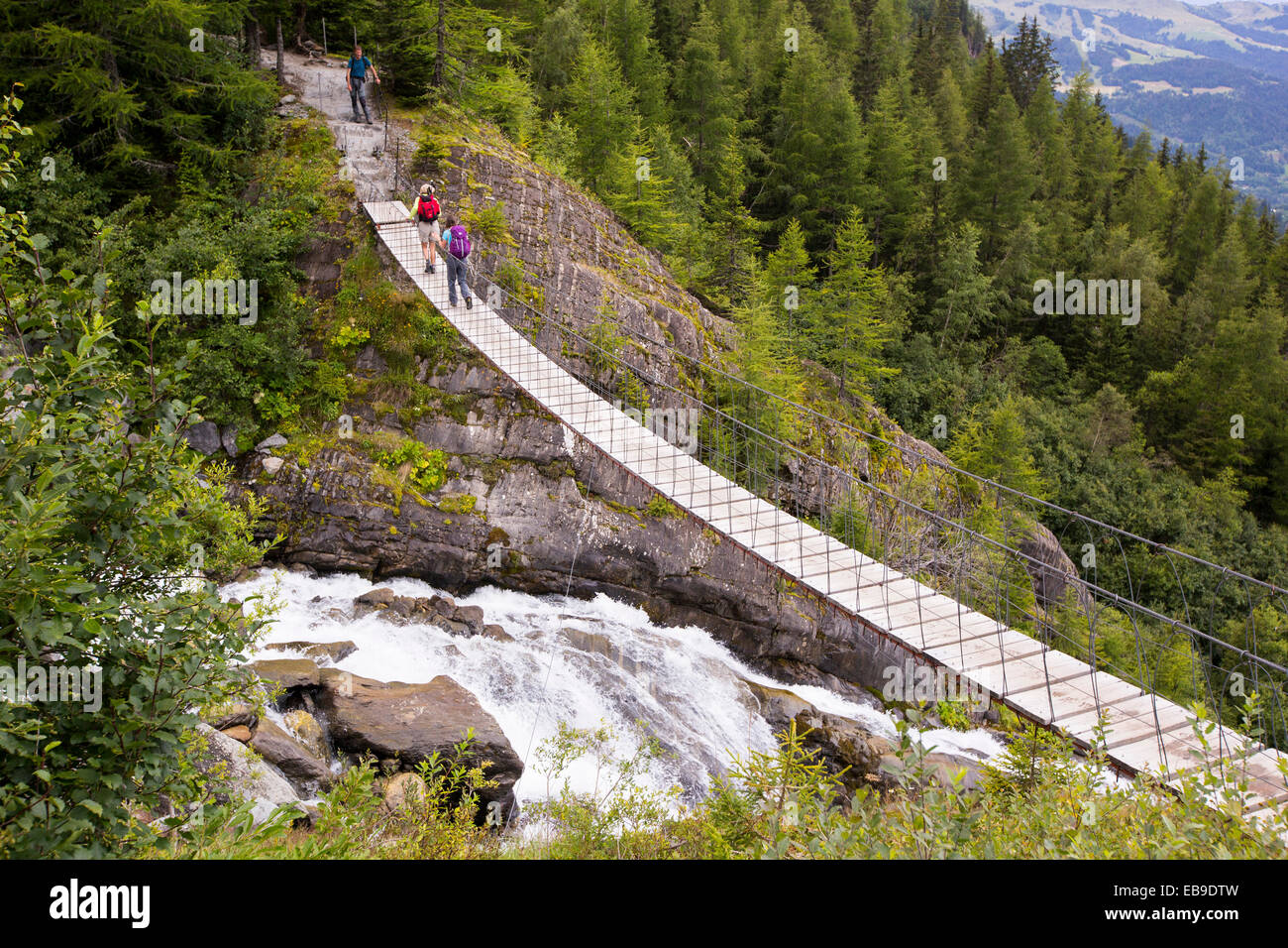 Walkers on the Tour Du Mont Blanc cross a suspension bridge across the ...