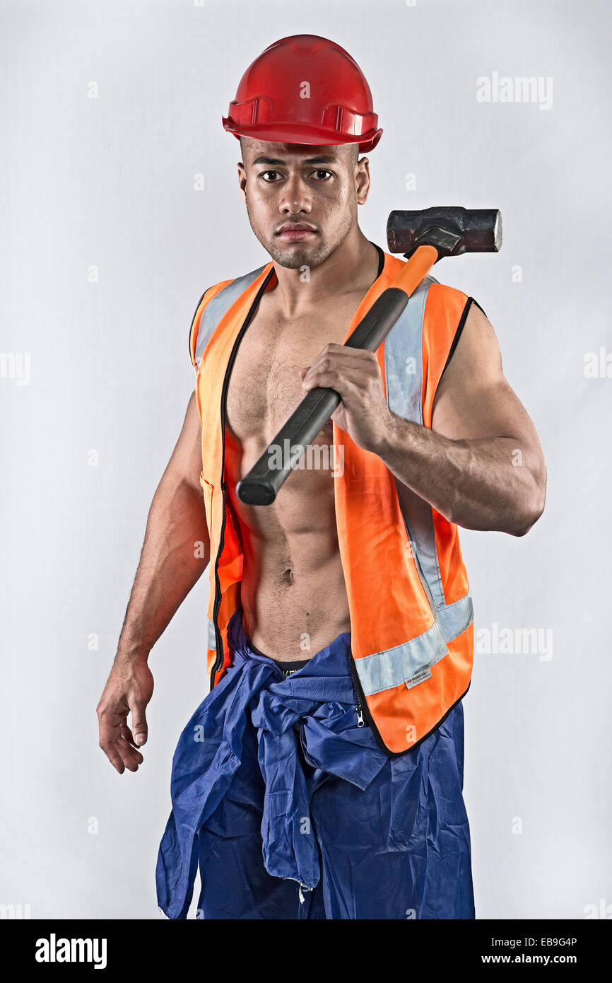 Young fit male shirtless workman with sledgehammer on shoulder wearing ...
