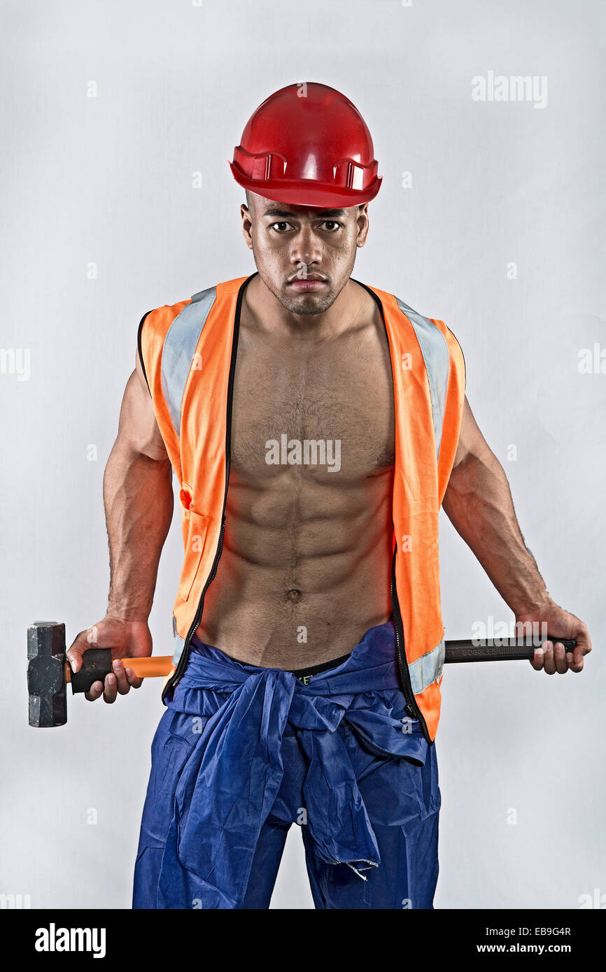 Young fit male shirtless workman with sledgehammer on shoulder wearing ...