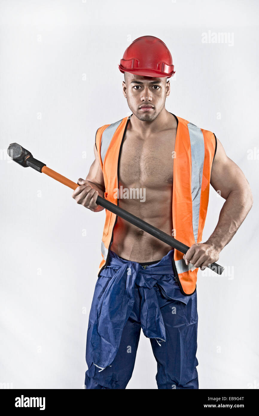 Young fit male shirtless workman with sledgehammer on shoulder wearing ...