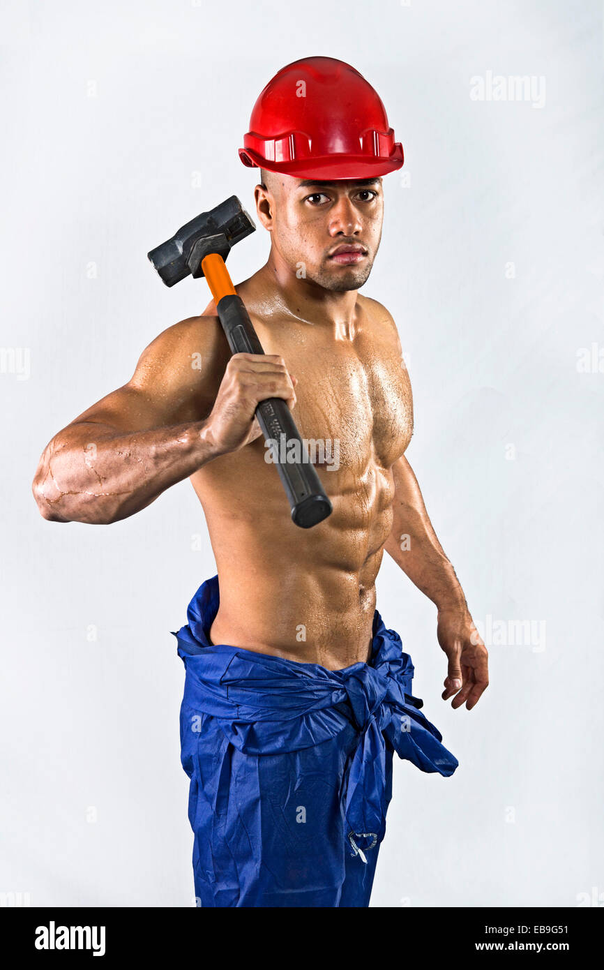Young fit male shirtless workman holding sledgehammer wearing red ...
