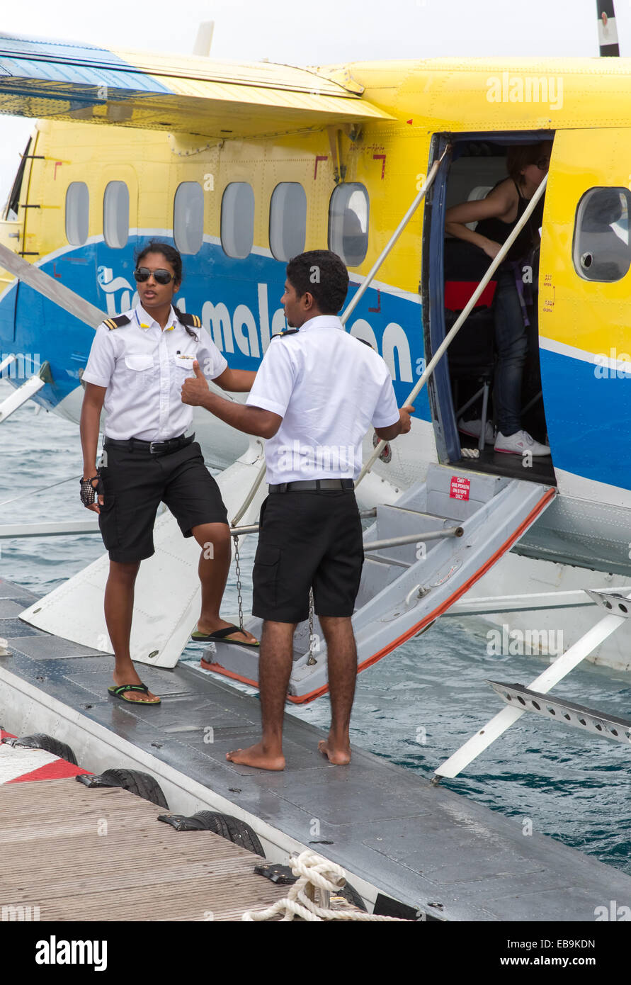A female pilot of Trans Maldivian Airways welcomes passengers onto a ...