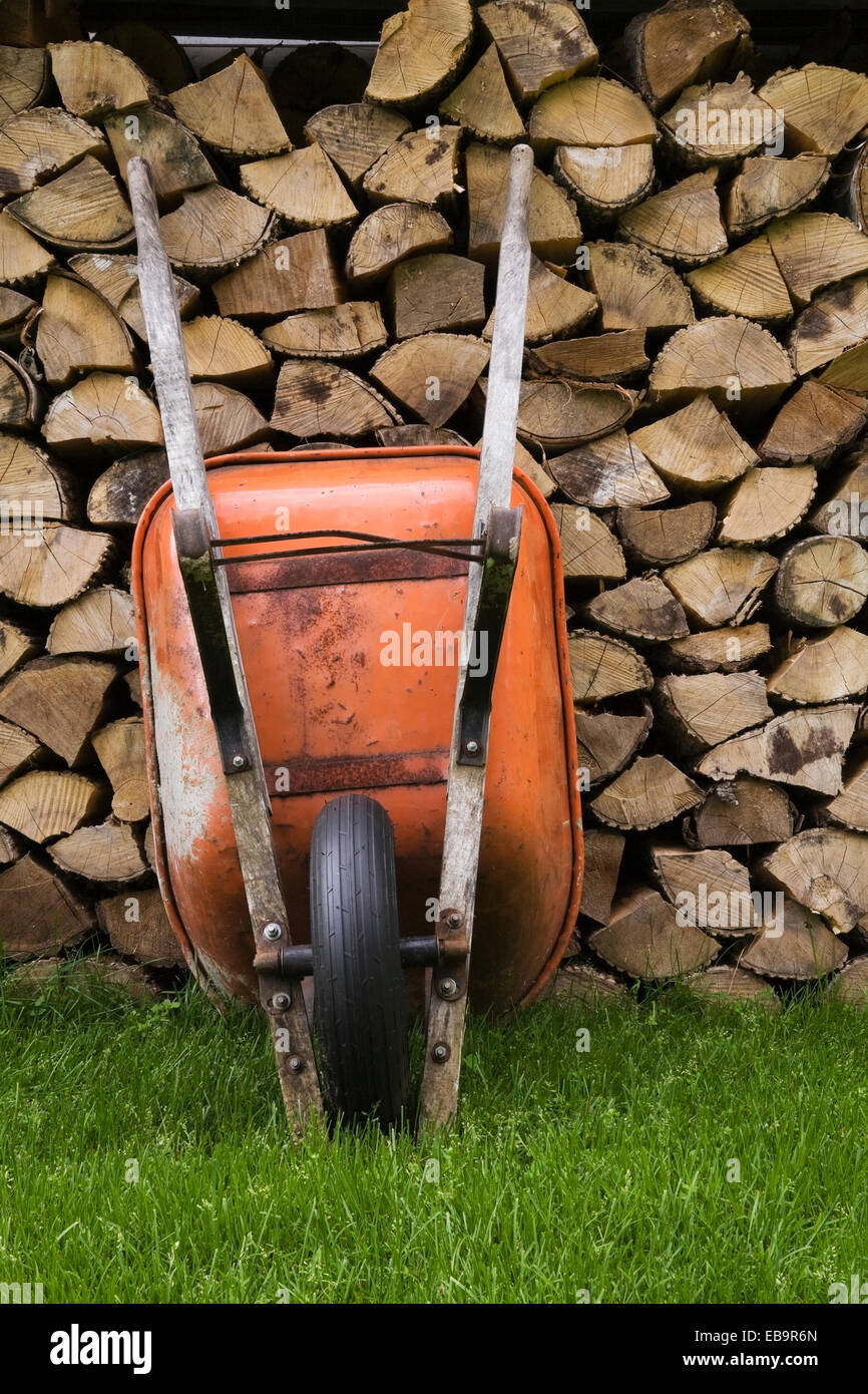 Orange wheelbarrow propped up against stacked firewood, Quebec City ...