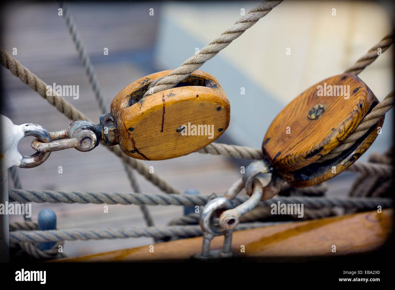closeup of wooden pulleys, ropes and shackles on deck of sailing boat ...
