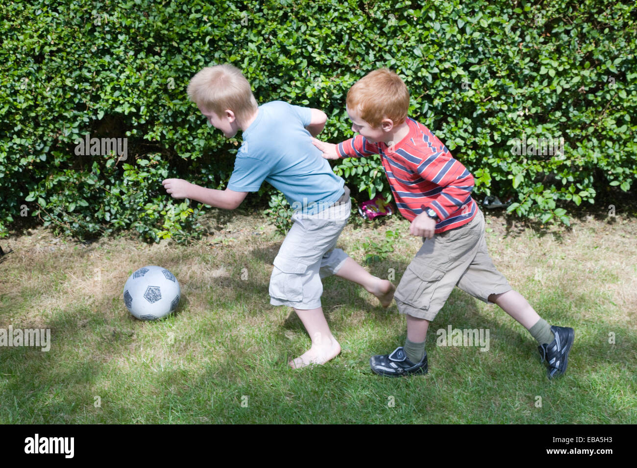 Two brothers playing football in the garden Stock Photo - Alamy