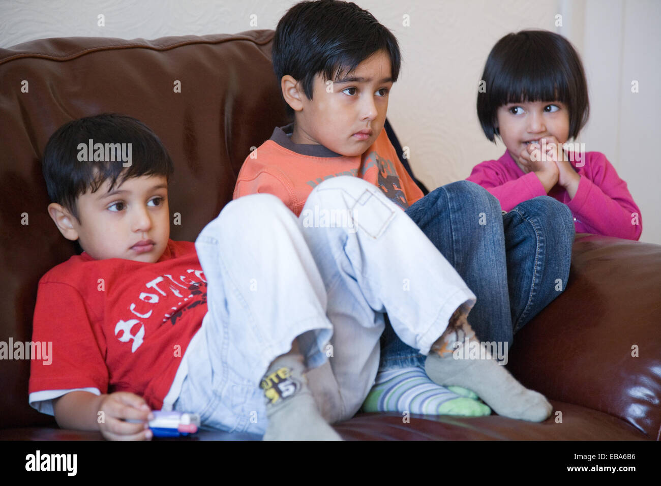Three children sitting at home watching television together Stock Photo ...