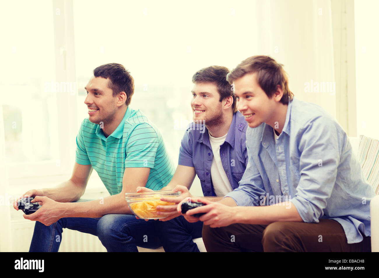 smiling friends playing video games at home Stock Photo - Alamy