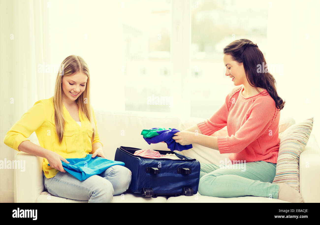 two smiling teenage girls packing suitcase at home Stock Photo - Alamy