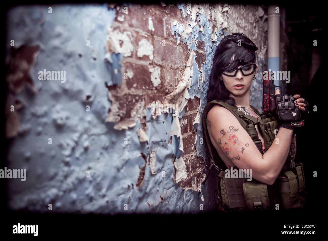 A young female dressed in protective safety clothing for airsoft games ...