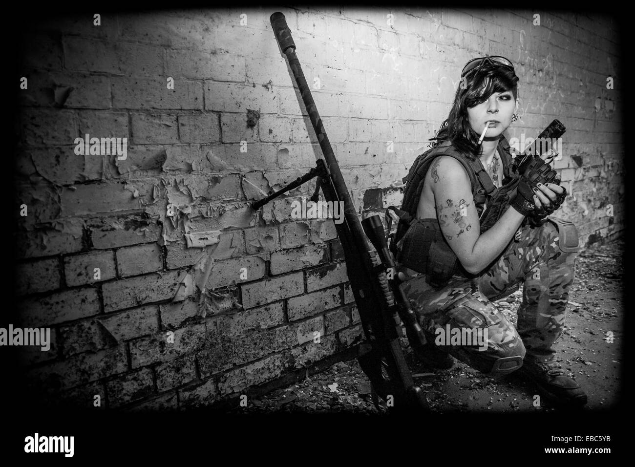 A young female dressed in protective safety clothing for airsoft games ...