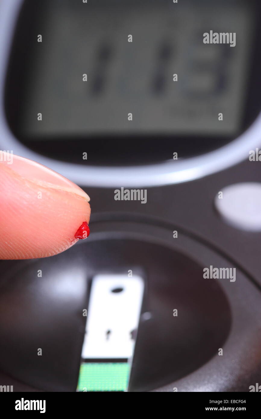 Closeup of finger with blood and glucose meter, taking blood sample ...