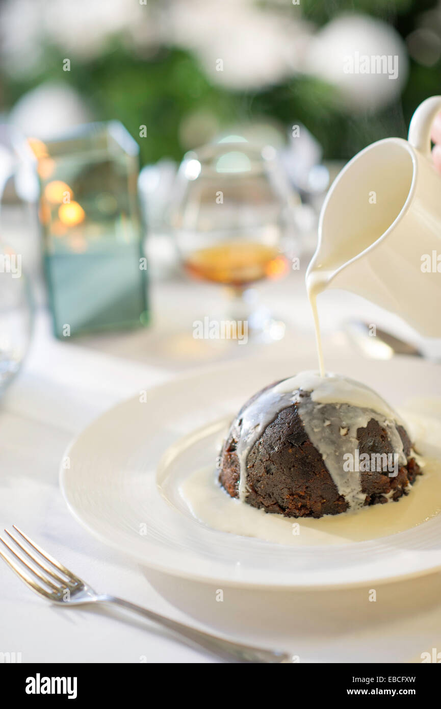 Cream being poured over Christmas pudding Stock Photo - Alamy
