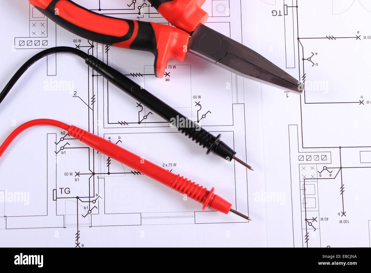 Cables of multimeter and metal pliers lying on construction drawings of ...
