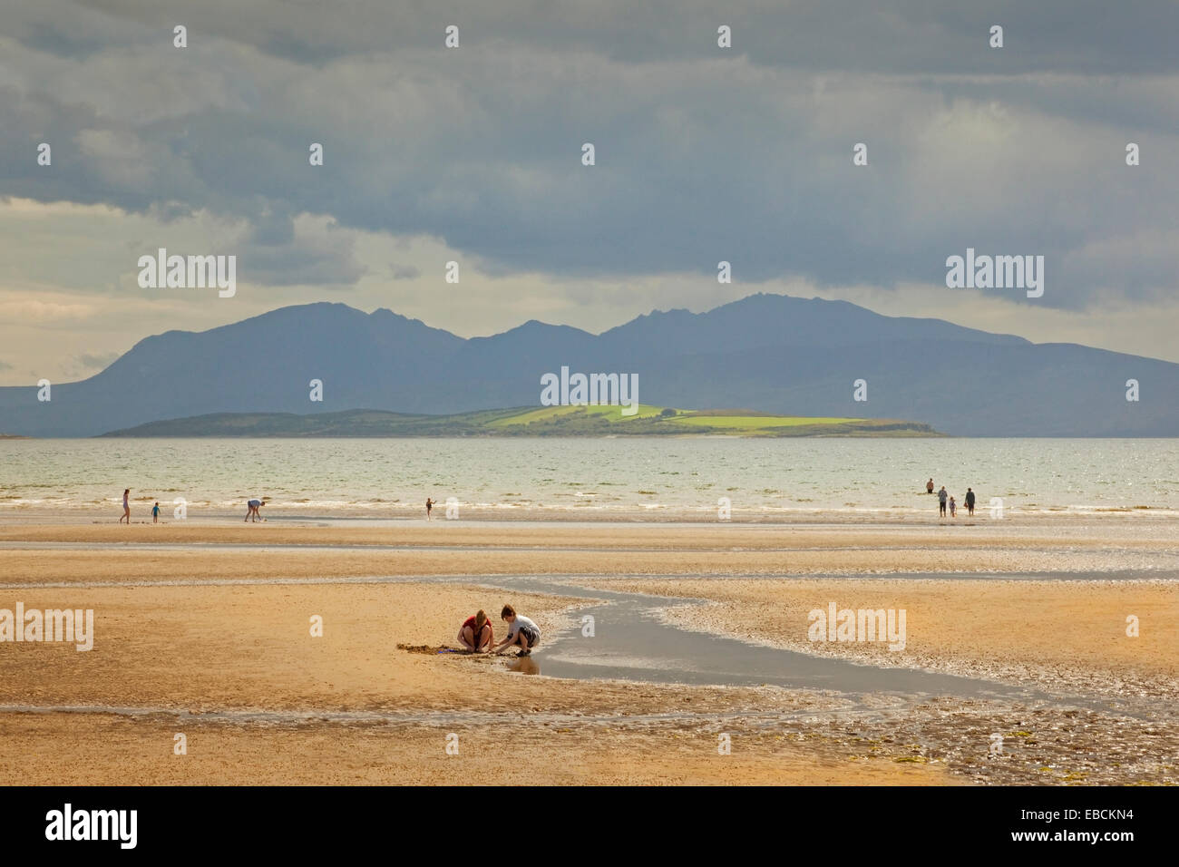 Families at Ettrick Bay on the Isle of Bute. The island of Inchmarnock ...