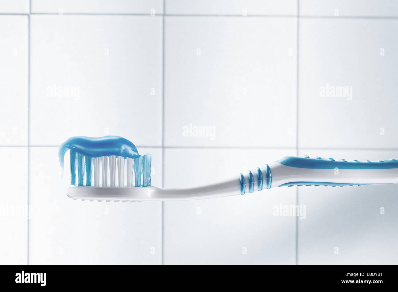 close up view of toothbrush and some toothpaste on it on white back ...