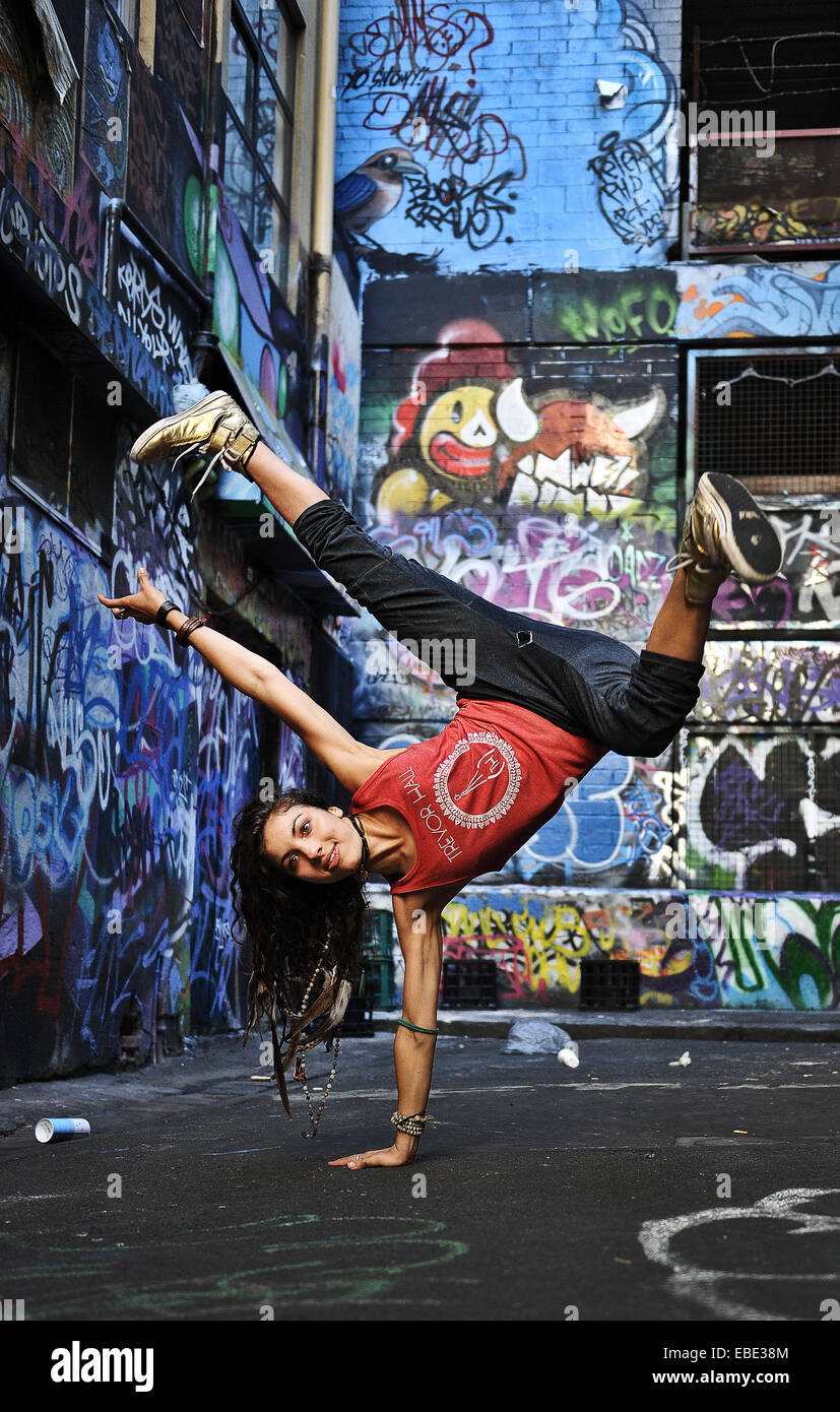 A dancer high kicking and flipping in a graffiti covered side street in ...