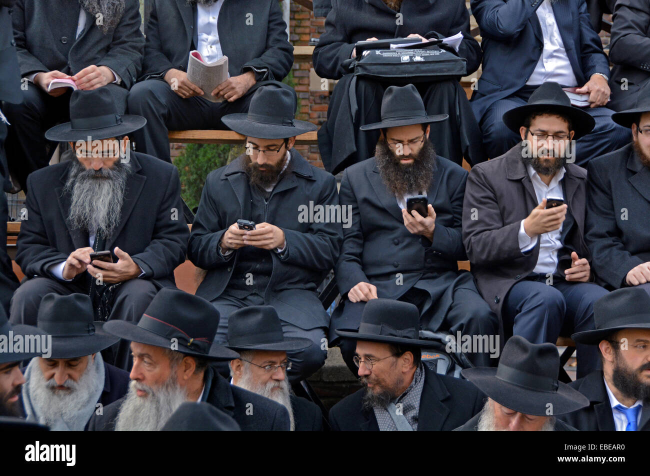 A group of orthodox rabbis, some texting on cell phones at a group ...