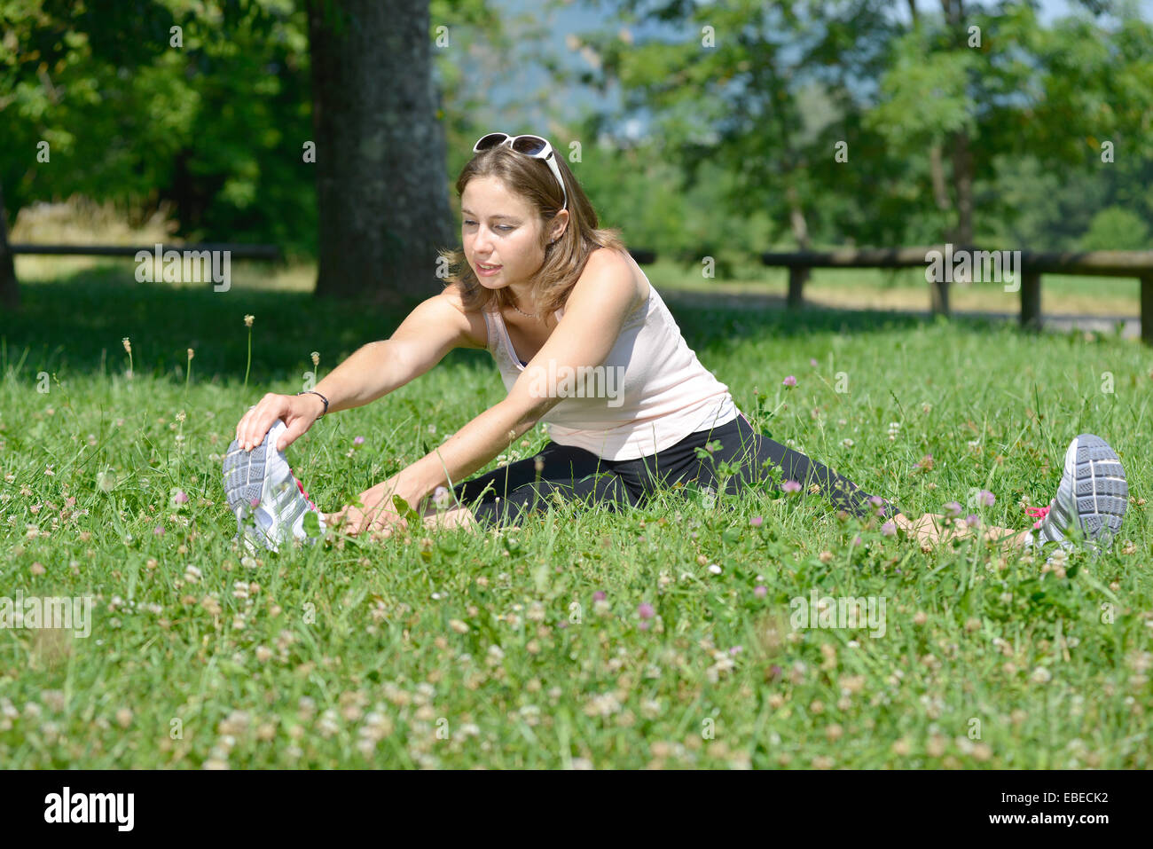 sporty young woman makes stretching exercises on grass Stock Photo - Alamy