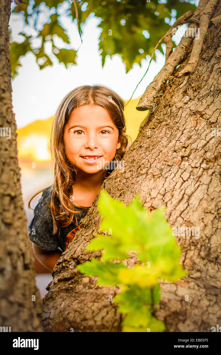 Little girl looking from behind the tree Stock Photo - Alamy