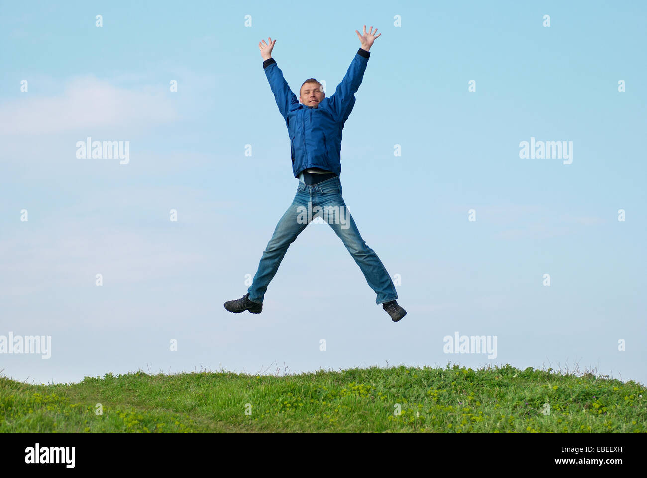 Jumping man on the hill with green grass Stock Photo - Alamy