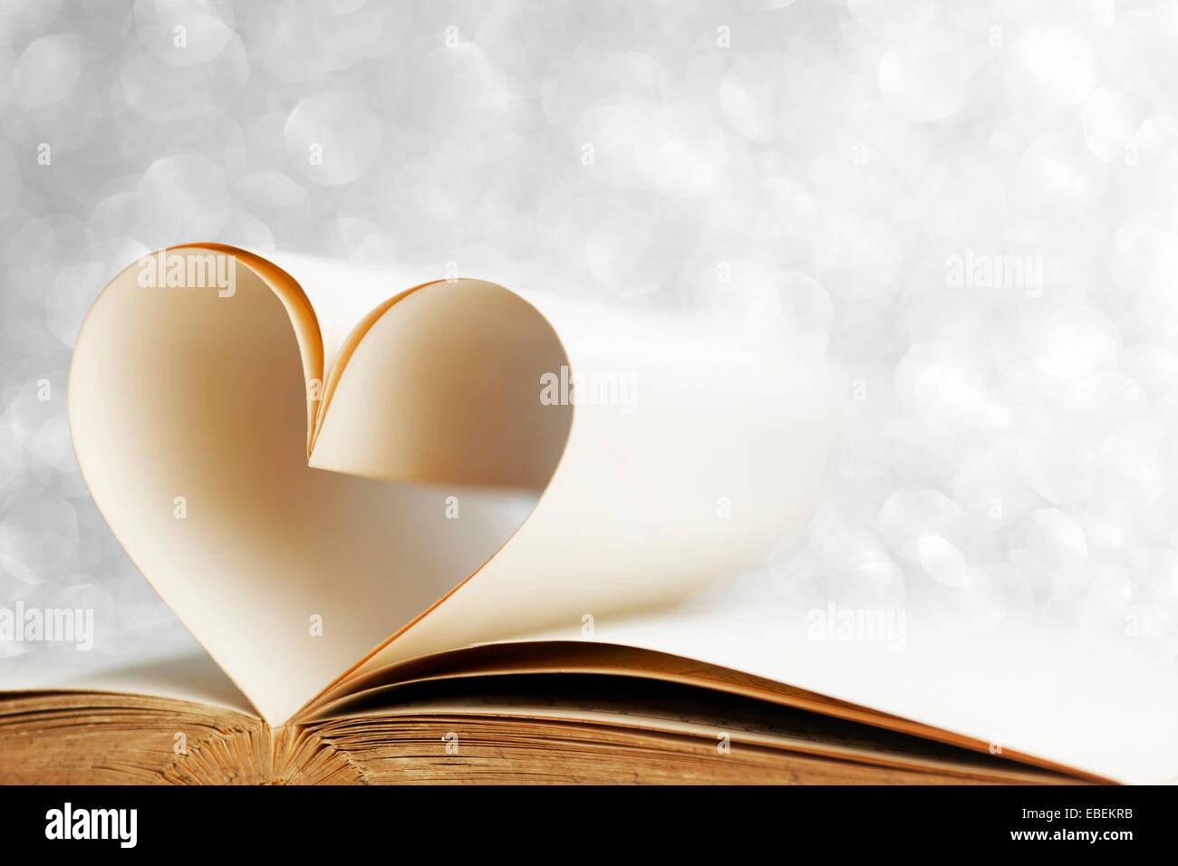 Heart shaped book pages on glitter background Stock Photo - Alamy