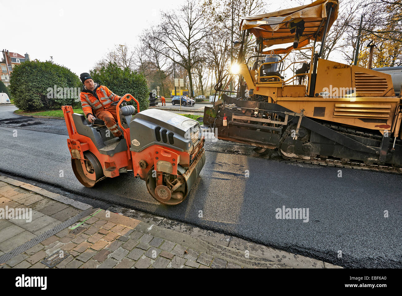 An asphalt spreader is used to place layer of asphalt and steam roller ...