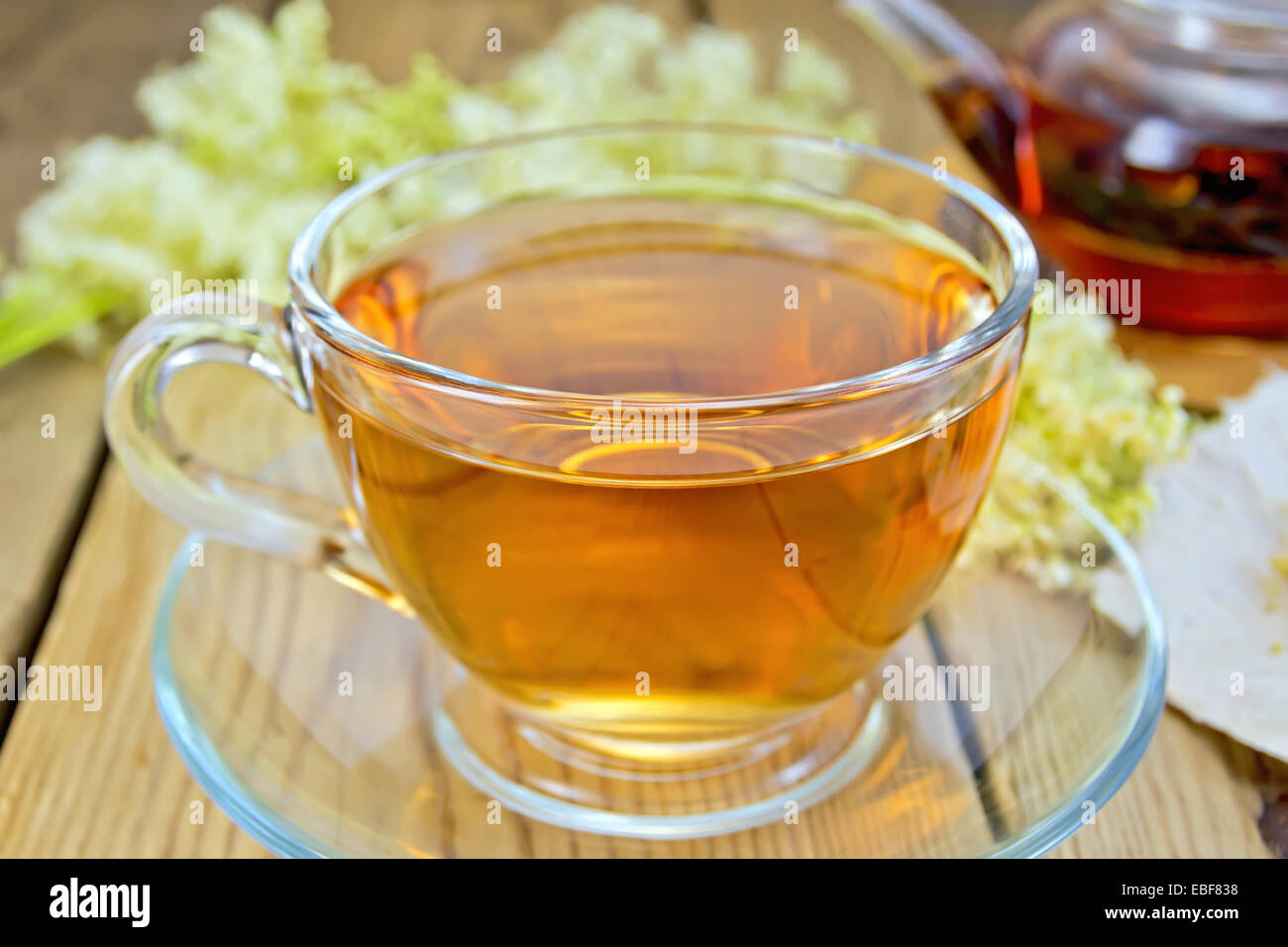 Tea from meadowsweet in glass cup and teapot on board Stock Photo - Alamy