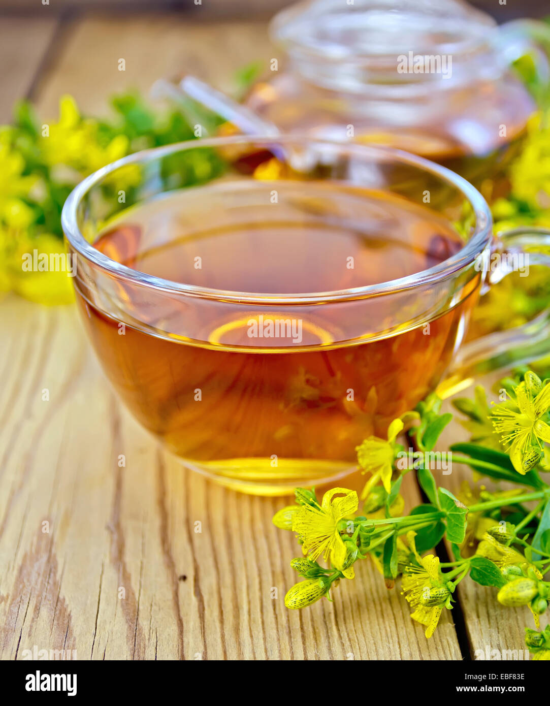 Tea from tutsan in glass cup and teapot on board Stock Photo - Alamy
