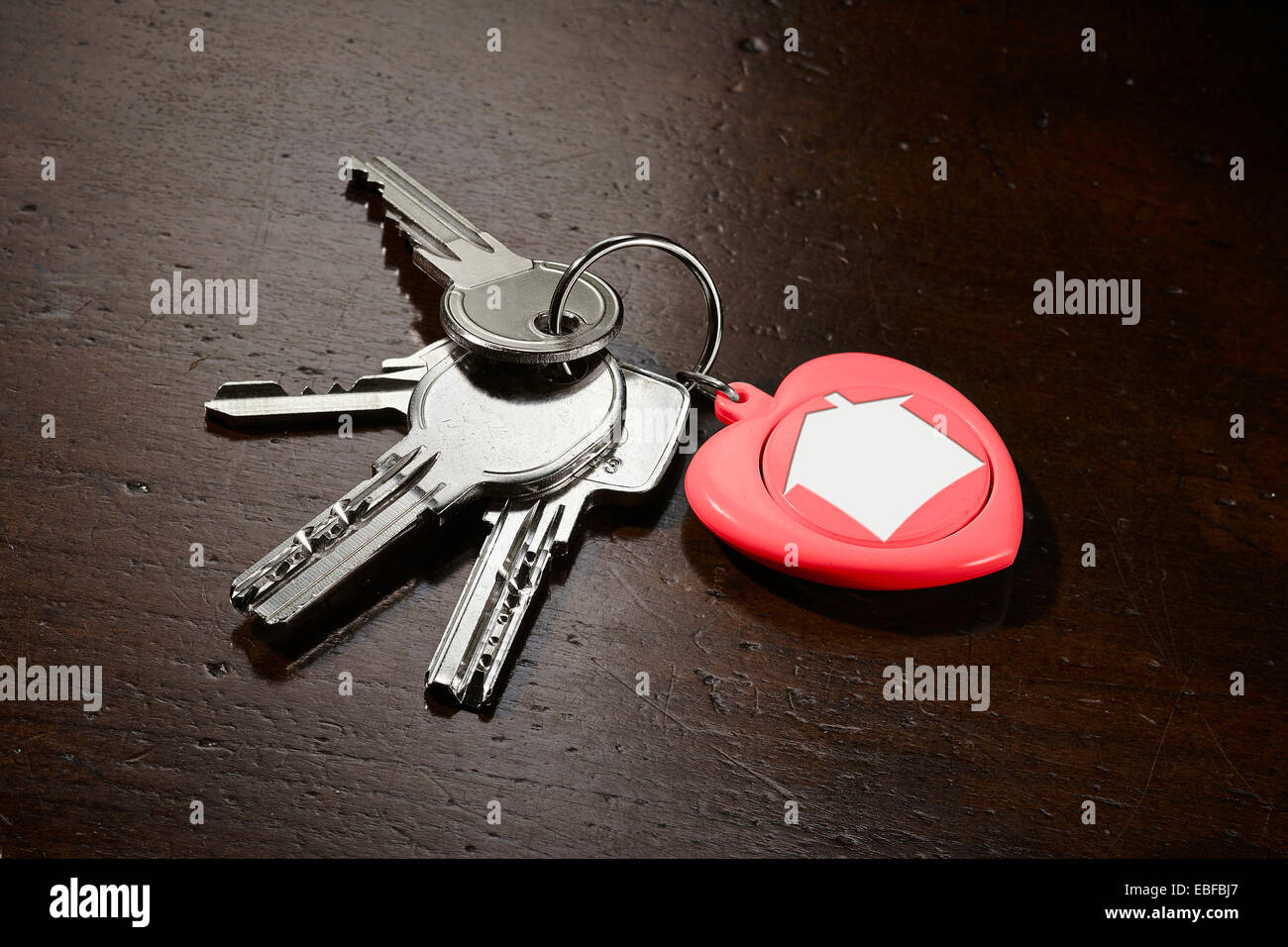 Set of house keys with a red keychain on dark brown wooden background ...