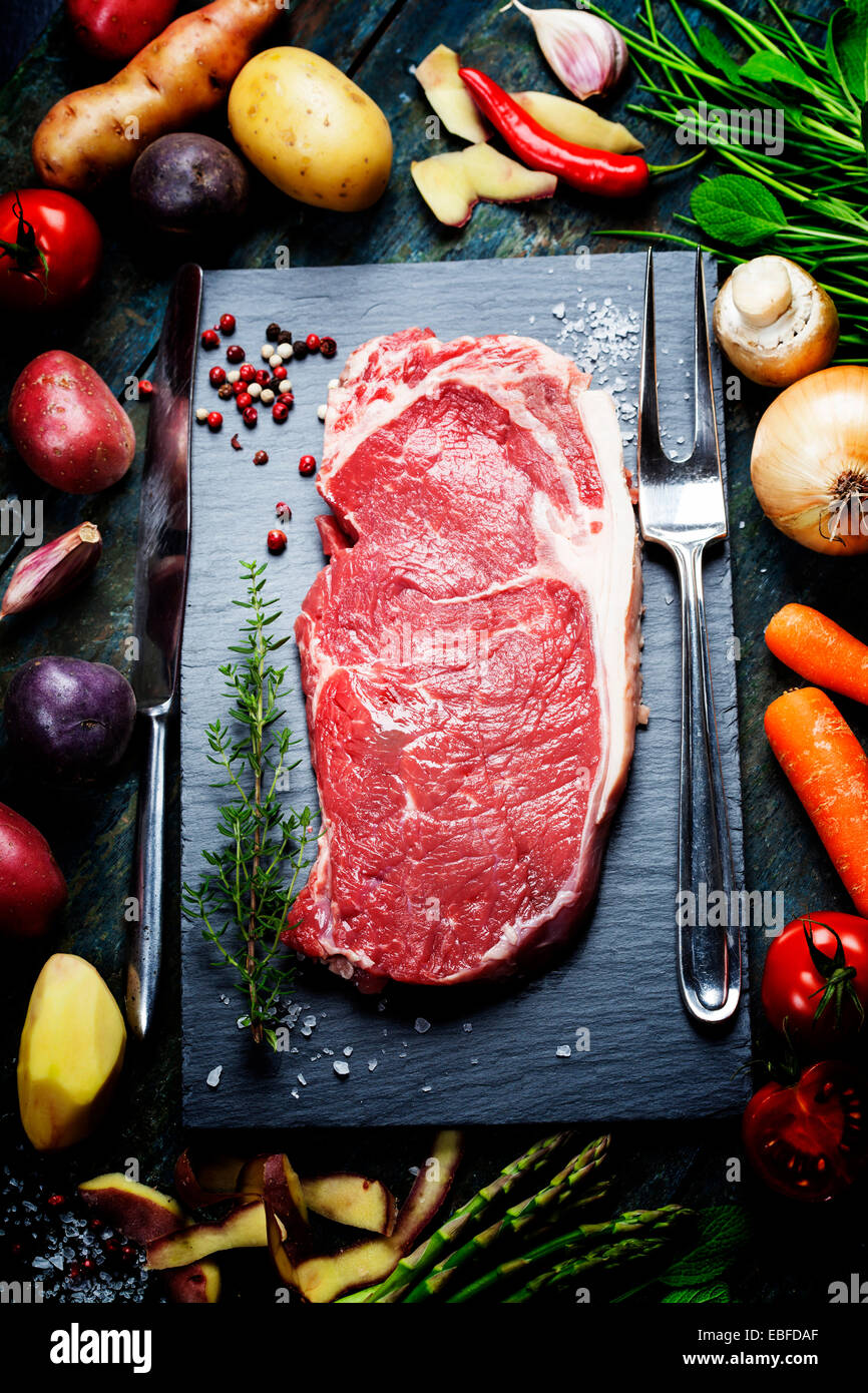 Food background with fresh vegetables and raw beef steak. Slate and ...