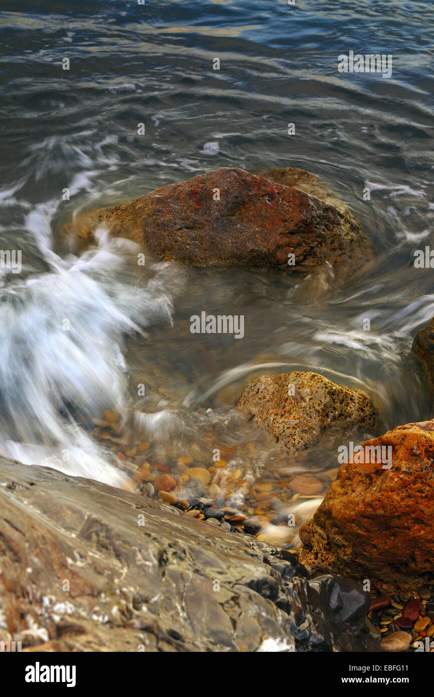 Swirling sea on rocky groyne Stock Photo - Alamy
