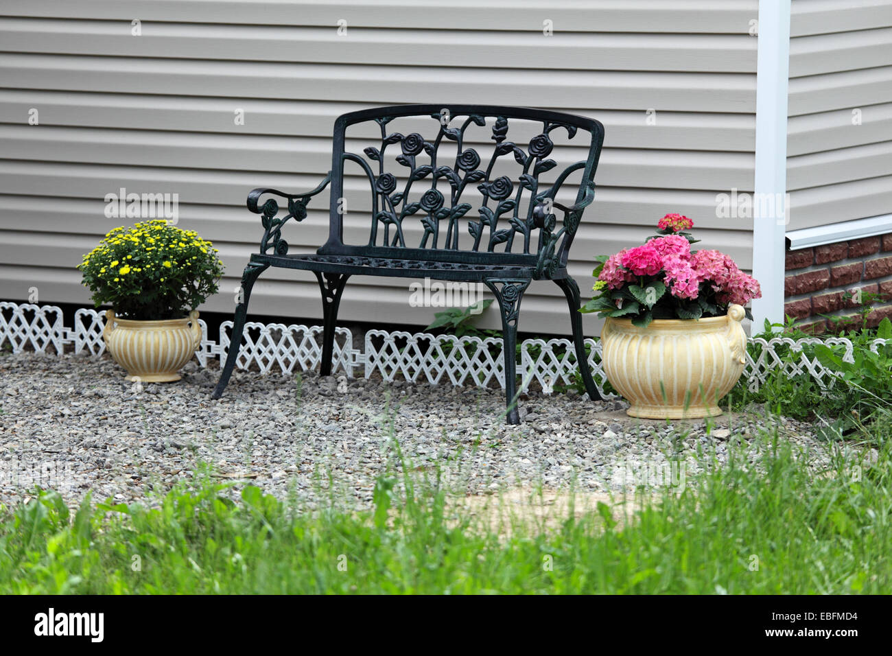 Iron bench and pots of flowers in the yard Stock Photo - Alamy