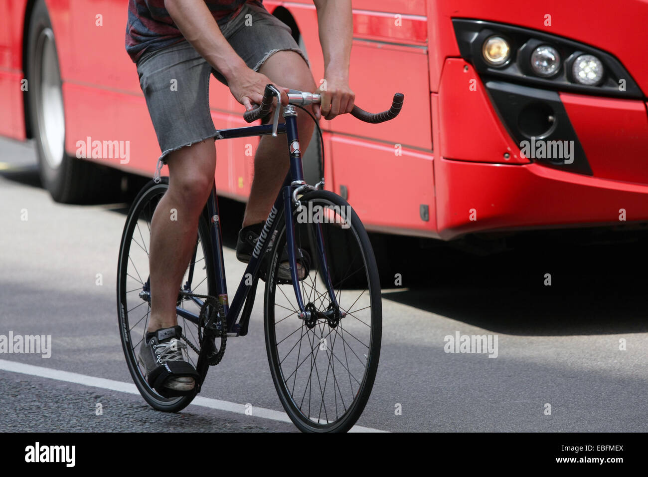A cyclist and red London bus traveling along a road Stock Photo - Alamy