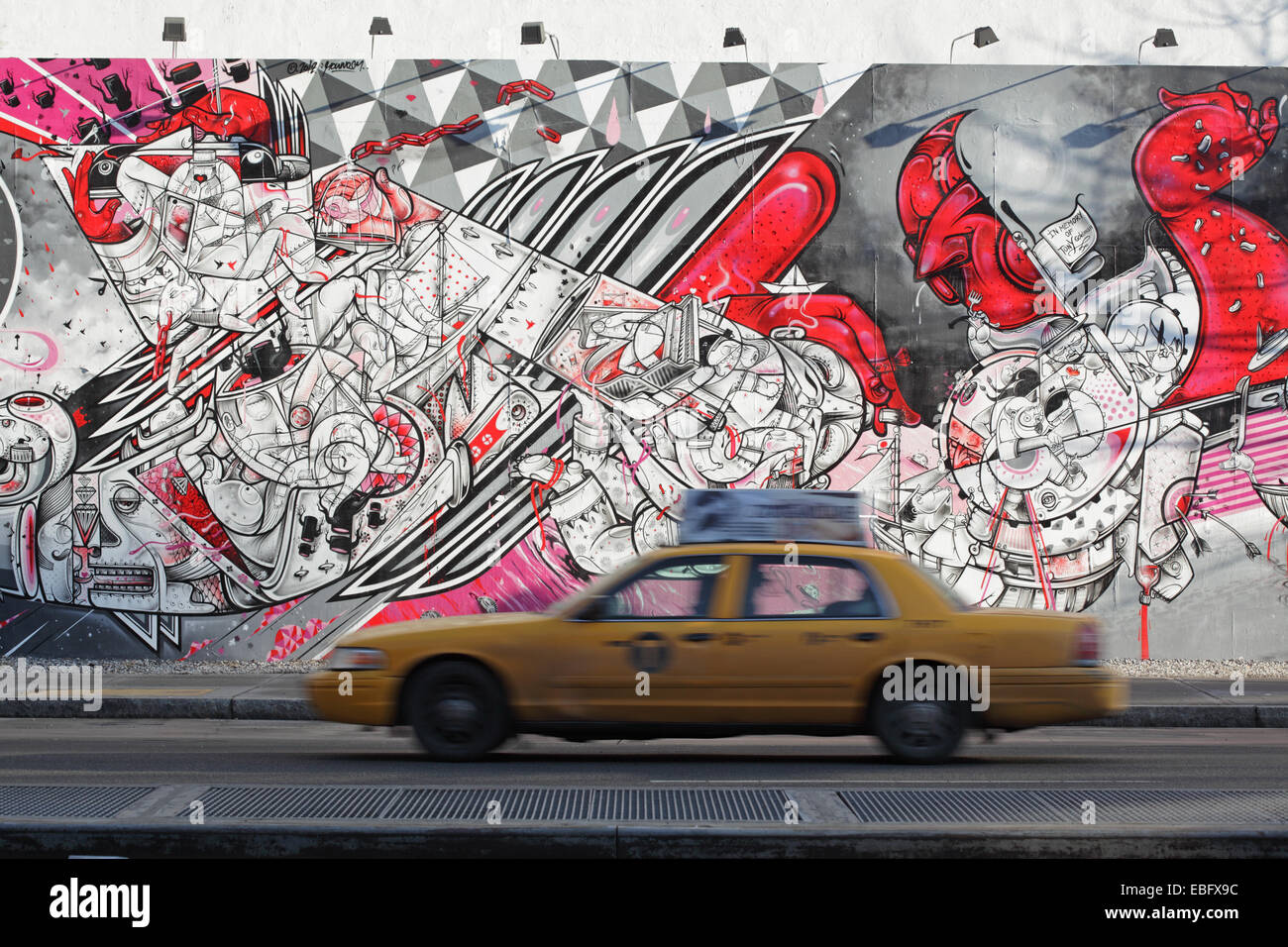 Yellow cab speeds past a brightly colored mural on the Bowery Mural ...