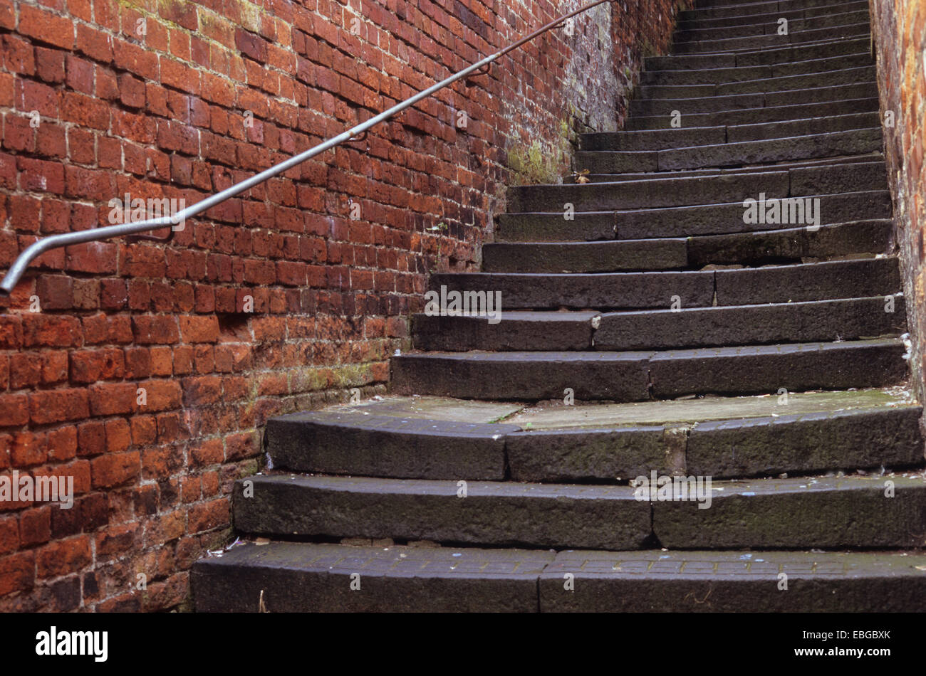 Long flight of steep stone steps rising between two brick walls with ...