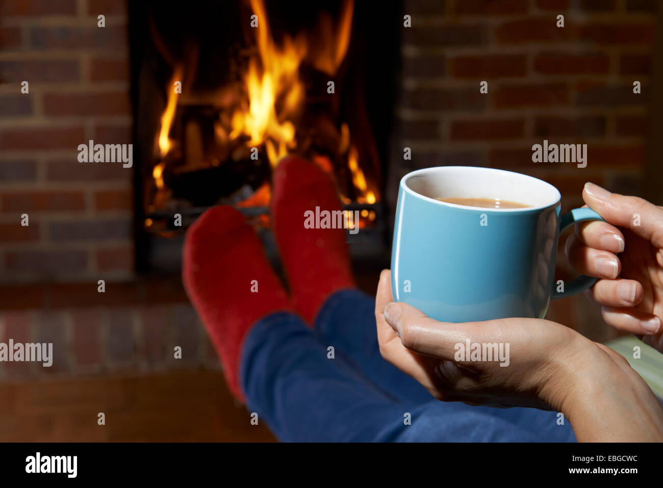 Woman With Hot Drink Relaxing By Fire Stock Photo - Alamy