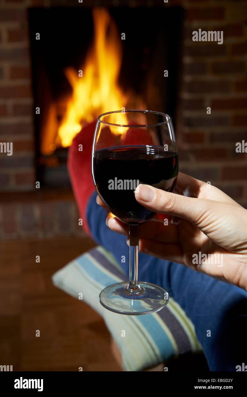 Woman With Glass Of Red Wine Relaxing By Fire Stock Photo - Alamy